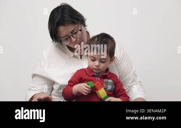 Adorable toddler boy sitting on his mothers lap and playing with ...