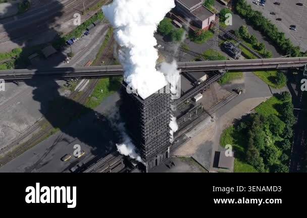 Industrial coke quenching tower releasing a large white steam plume ...