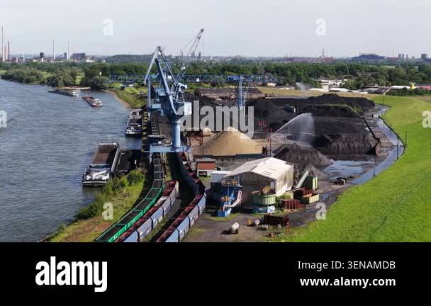 Aerial view of a large port crane transloading coal from a river barge ...