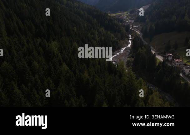 Aerial drone footage tilting up from a winding river and dense pine ...