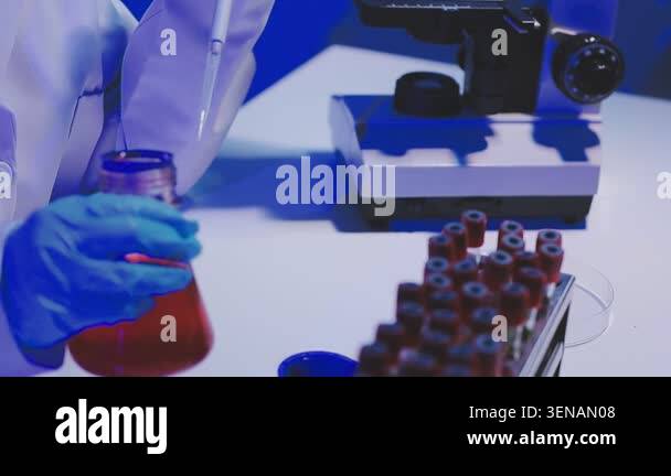 laboratory scientist in blue coat holding tube and looking at camera ...