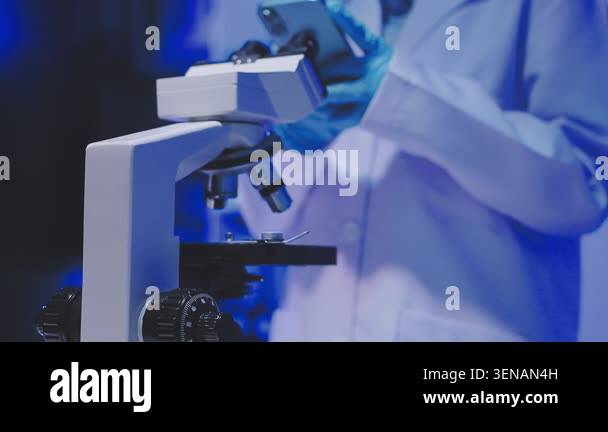 laboratory assistant holding a microscope with a blue liquid Stock ...