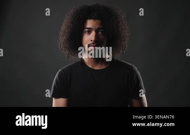 Confident Young Man With Afro Hairstyle And Dark T-Shirt Posing Against ...