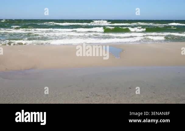 Continuous motion of green sea waves rolling onto smooth beige sand ...