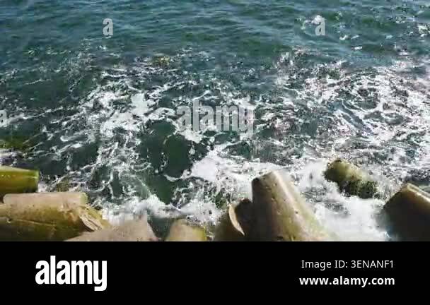 Powerful ocean waves collide with large cylindrical concrete blocks ...
