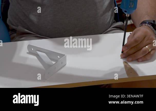 Carpenter drills a screw into a white wooden plank using an electric ...