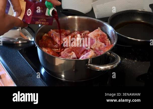 Unrecognizable chef marinating pork ribs with red wine and water in a ...