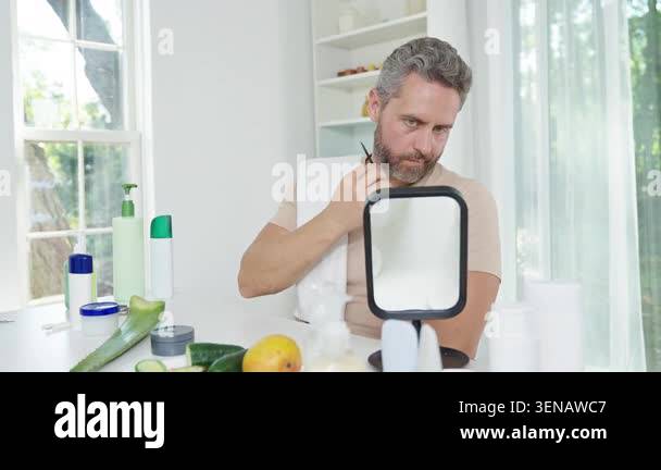 Bearded man combing beard after shower. Bearded man styling beard for ...