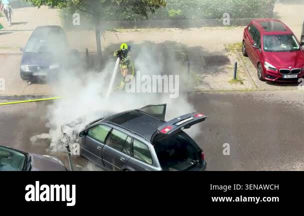 Dense smoke spreads across a city street as a firefighter works behind ...