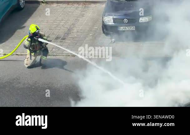 A firefighter sends a long water jet across an urban road toward a ...