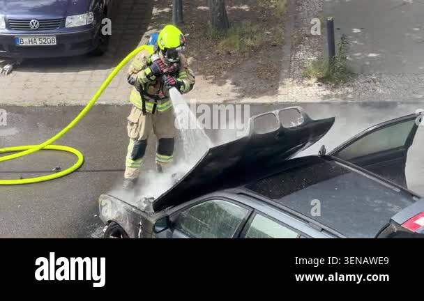A firefighter uses a hose to cool a damaged vehicle after flames burned ...