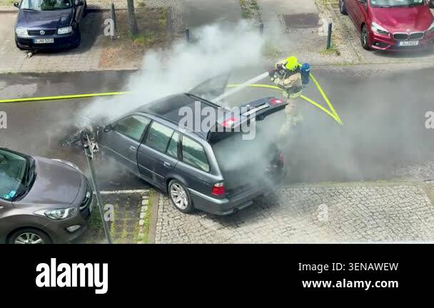 A firefighter sprays water across the street toward a smoke filled ...