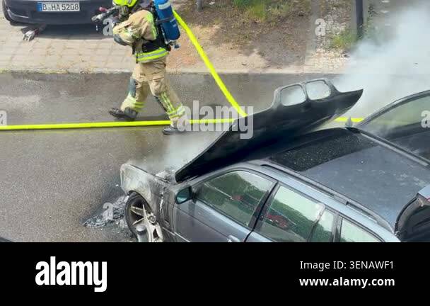 A firefighter checks a burned station wagon with the hood open after an ...