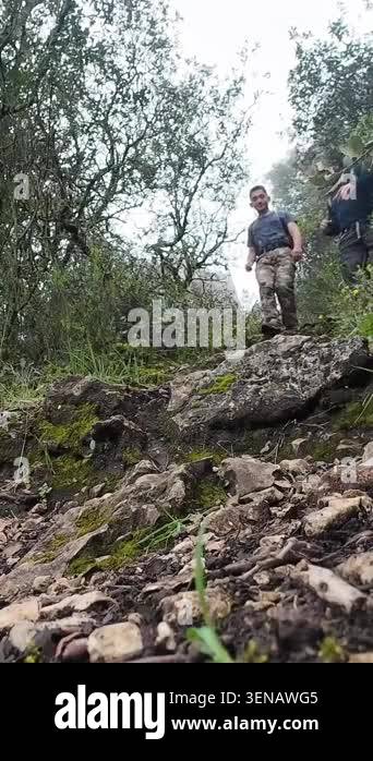 Two adventurous men carefully walking down a steep, rocky path in a ...