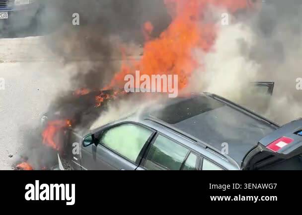 Large flames rise above the roof of a burning station wagon as smoke ...