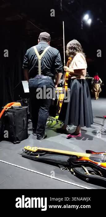 Fixed-camera long shot of two musicians seen from behind, conversing on ...