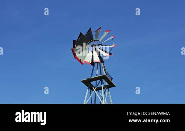 A windmill stands tall in a rural area, turning gently in the wind ...
