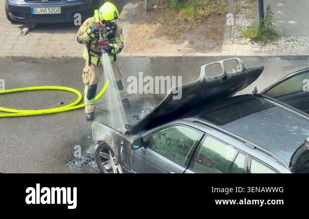 A firefighter in protective gear sprays water into the burned front of ...