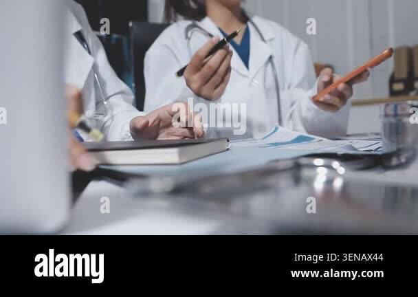 young doctor in uniform writing in notebook while working with laptop ...