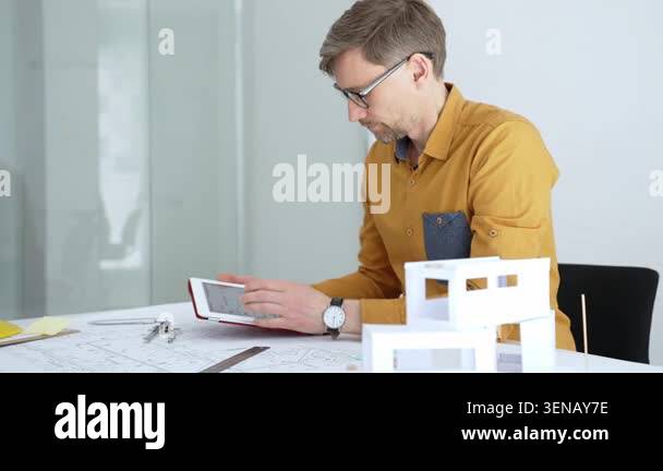 Professional architect concentrating on architectural blueprints and a ...