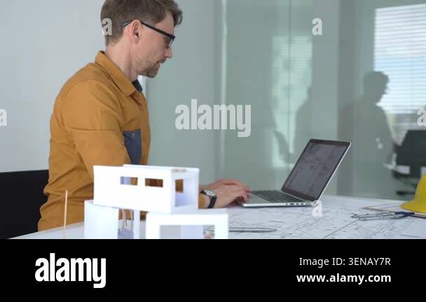 Male architect concentrating on constructing a detailed architectural ...