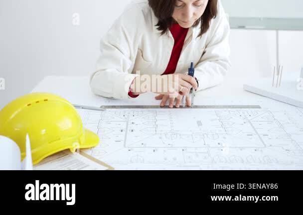Woman architect drafting detailed blueprints at desk with ruler and pen ...
