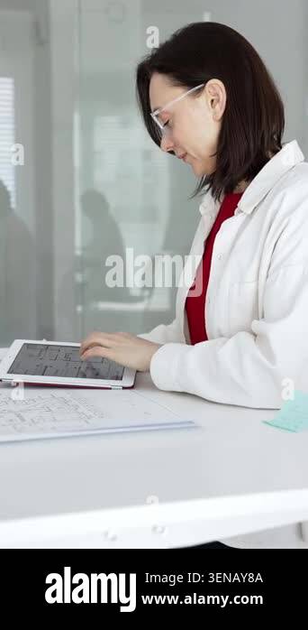 Woman architect working on a new design, evaluating architectural plans ...