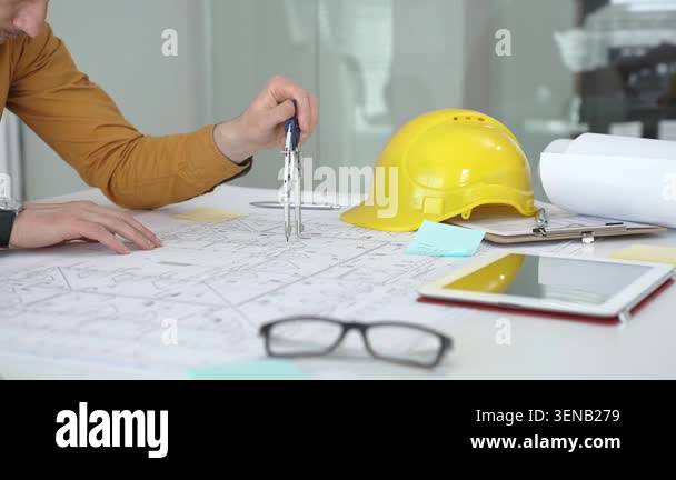 Engineers hands sketching and annotating architectural blueprints on a ...