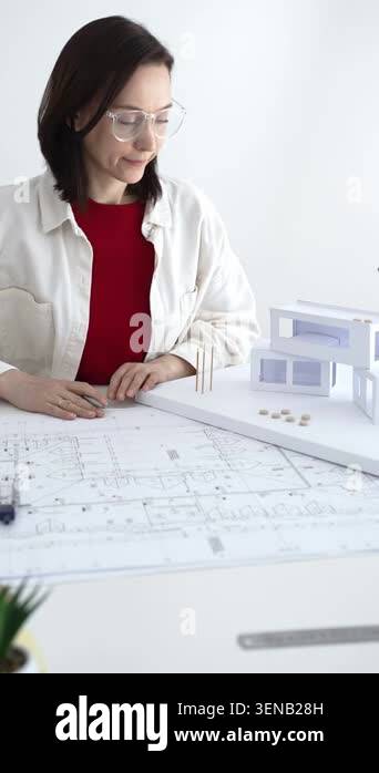 Architect analyzing building blueprints and typing on a laptop ...
