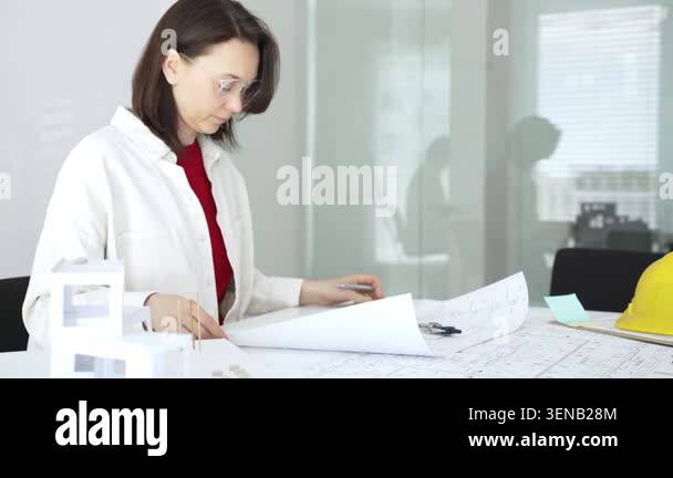 Woman architect focusing on architectural drawings and blueprints ...