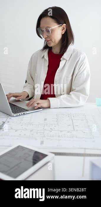 Woman architect working on a new design, evaluating architectural plans ...