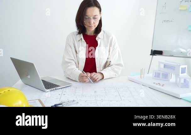 Architect analyzing building blueprints and typing on a laptop ...