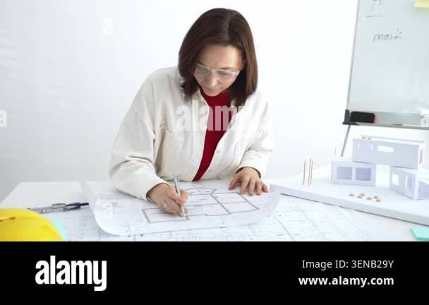 Architect analyzing building blueprints and typing on a laptop ...