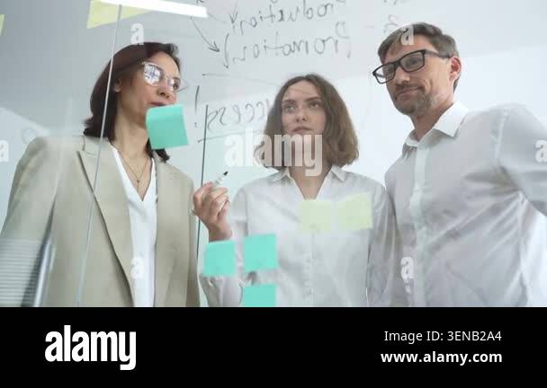 Business professionals collaborating on a transparent glass board ...