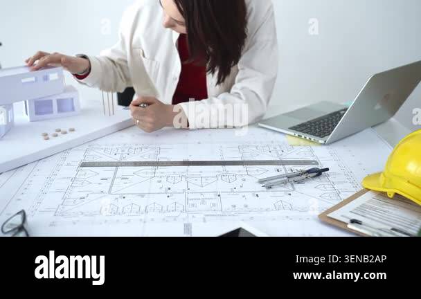Architect analyzing building blueprints and typing on a laptop ...