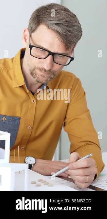 Male architect concentrating on constructing a detailed architectural ...
