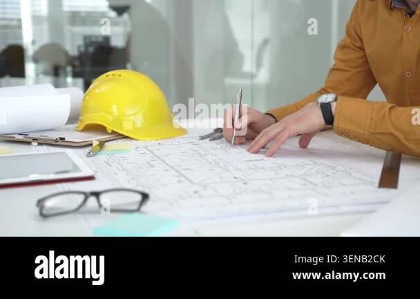 Engineers hands sketching and annotating architectural blueprints on a ...