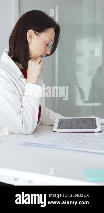 Woman architect working on a new design, evaluating architectural plans ...