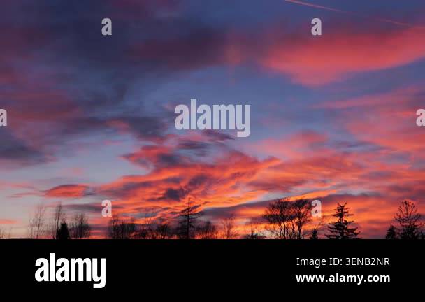 A wide shot of colorful sunset clouds in shades of pink, orange, and ...
