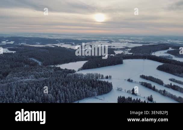 Aerial panorama of snowy meadows, dark forest edges, rolling winter ...