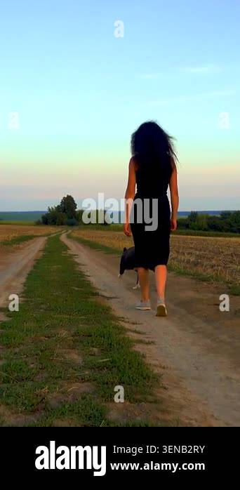 A beautiful young woman walks with a Staffordshire Terrier in a field ...