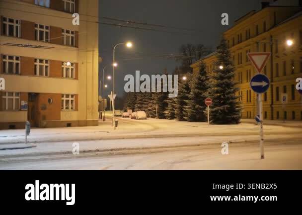 A quiet urban street covered in snow during a winter night. The scene ...
