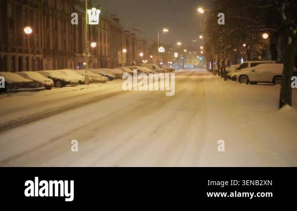A quiet urban street covered in thick snow during a winter night ...