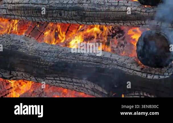 Close detail of a charred log burning with bright flames, glowing ...