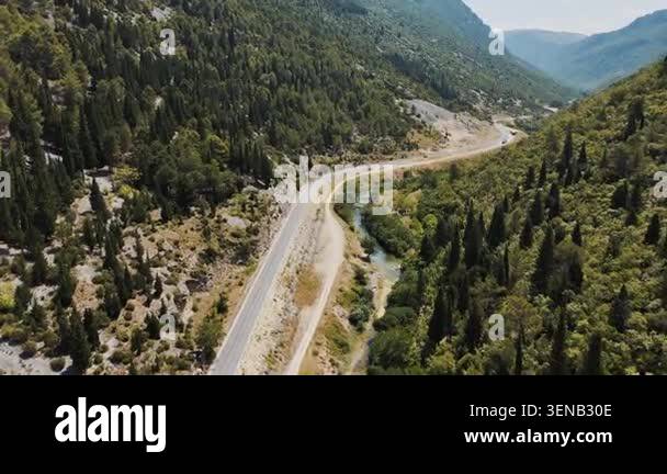 An aerial drone shot shows a winding asphalt road snaking through a ...