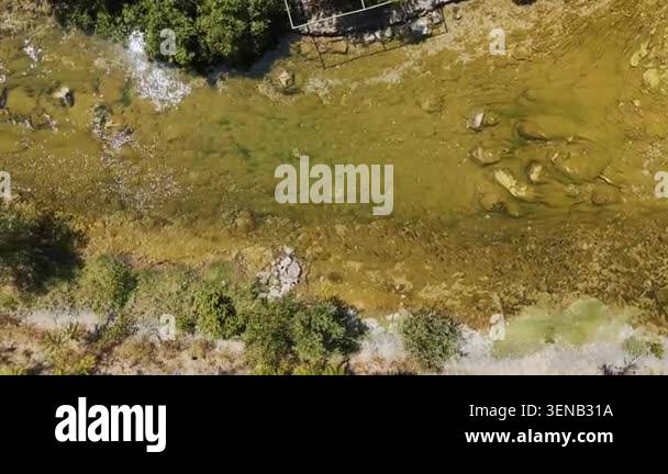An aerial top-down view shows clear turquoise water flowing over a ...