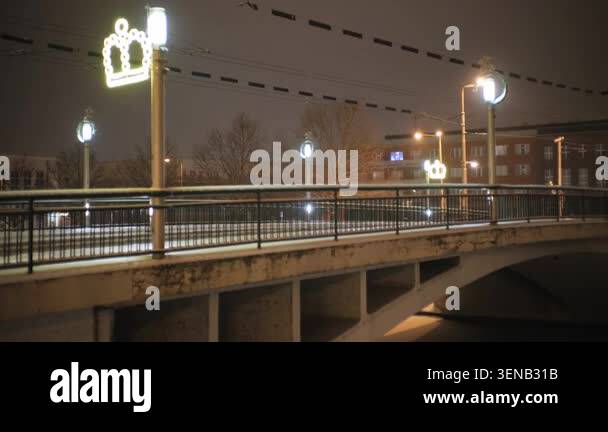 A night view of a concrete bridge with metal railings over a river ...