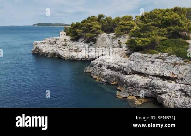 An aerial view shows a rugged rocky coastline with turquoise water ...