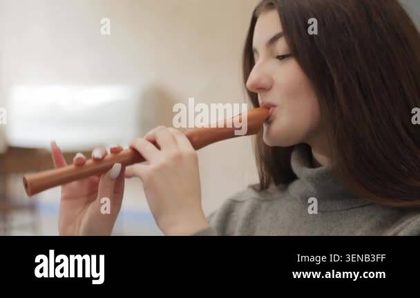 Beautiful young woman with long hair playing a traditional woodwind ...