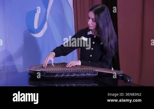 Elegant female musician playing a gusli, a traditional plucked string ...